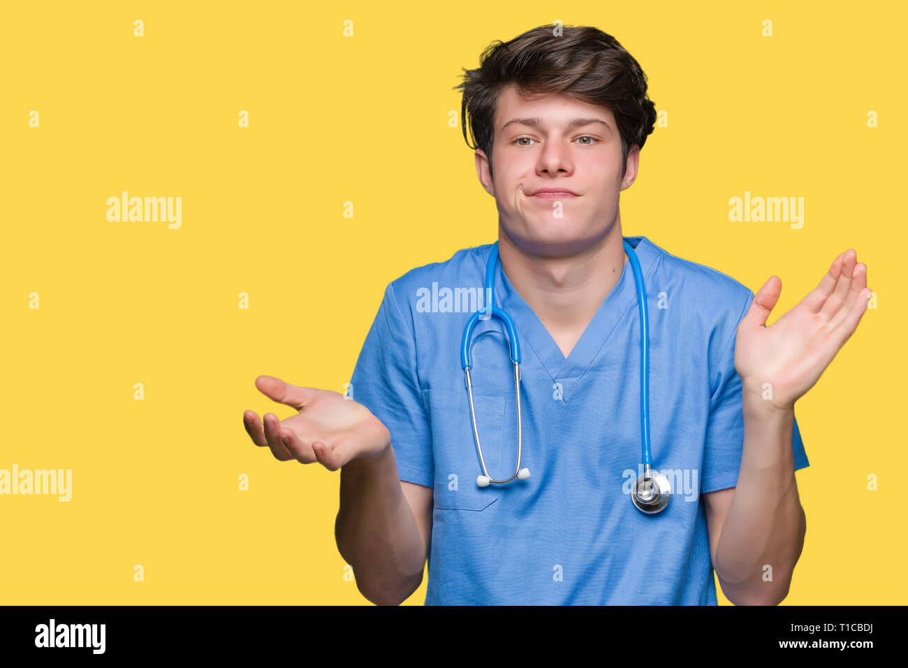 Young doctor wearing medical uniform over isolated background clueless ...
