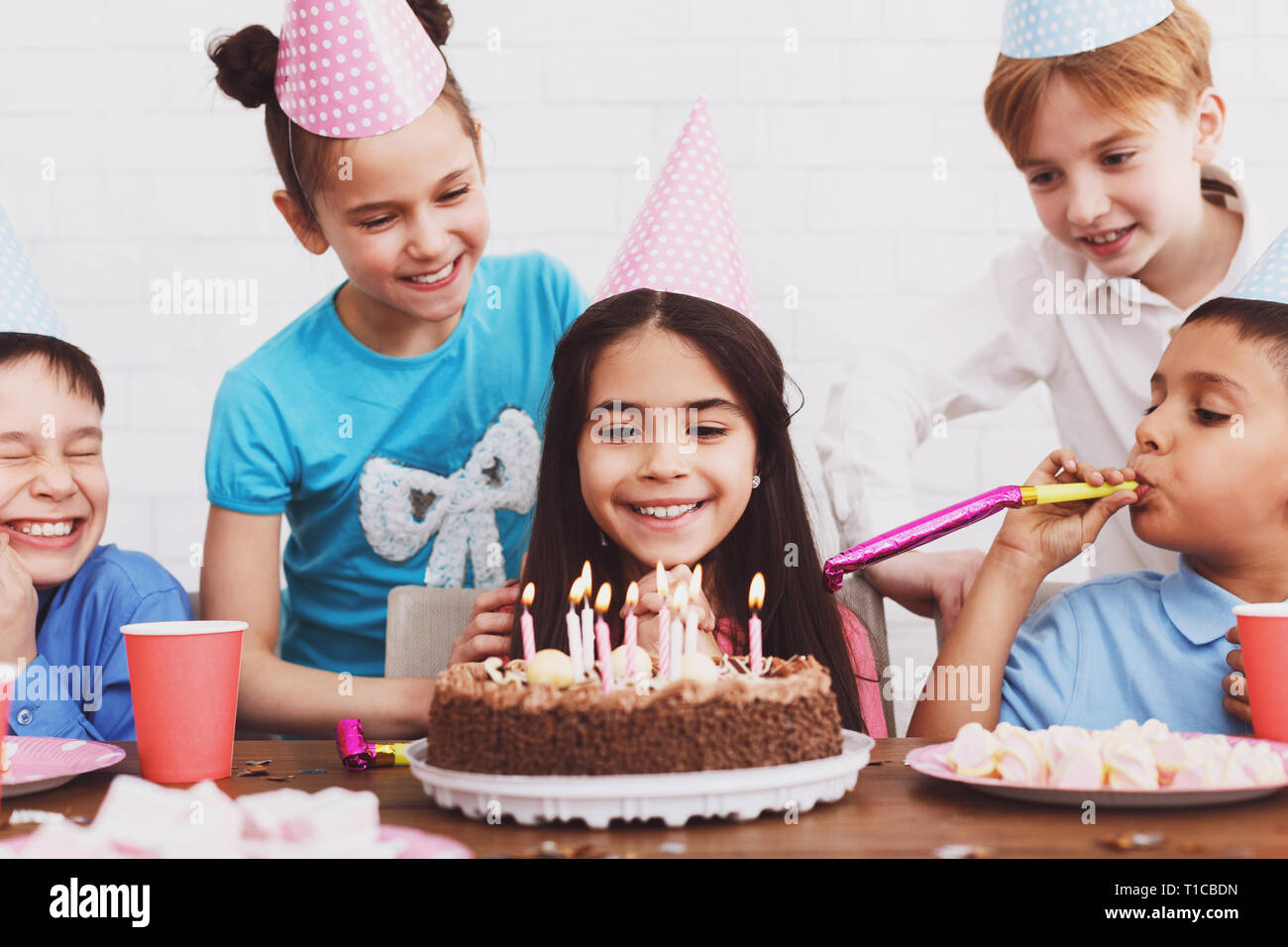 Kids looking at birthday cake with candles Stock Photo - Alamy