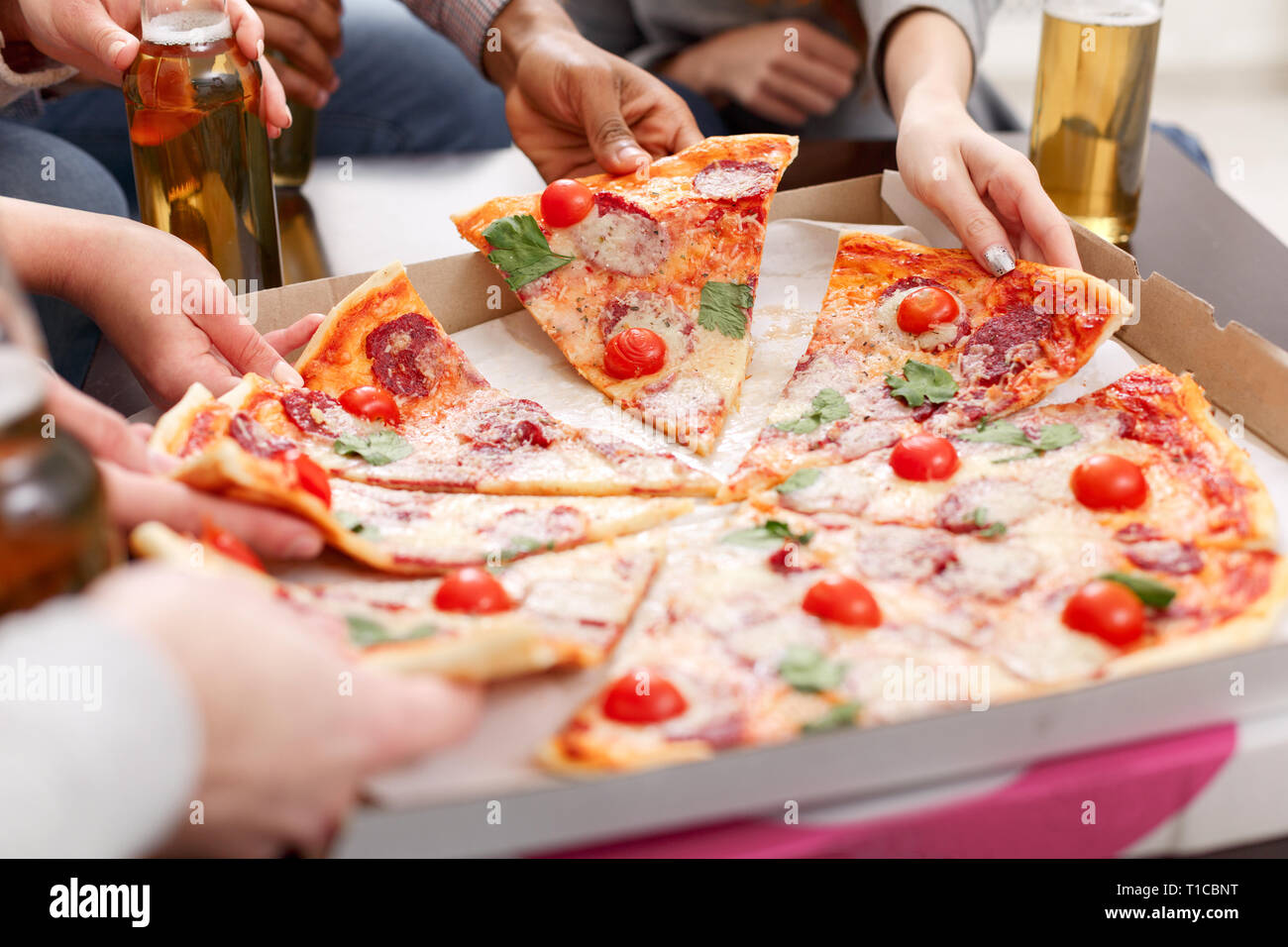Friends eating delicious pizza at home party Stock Photo - Alamy