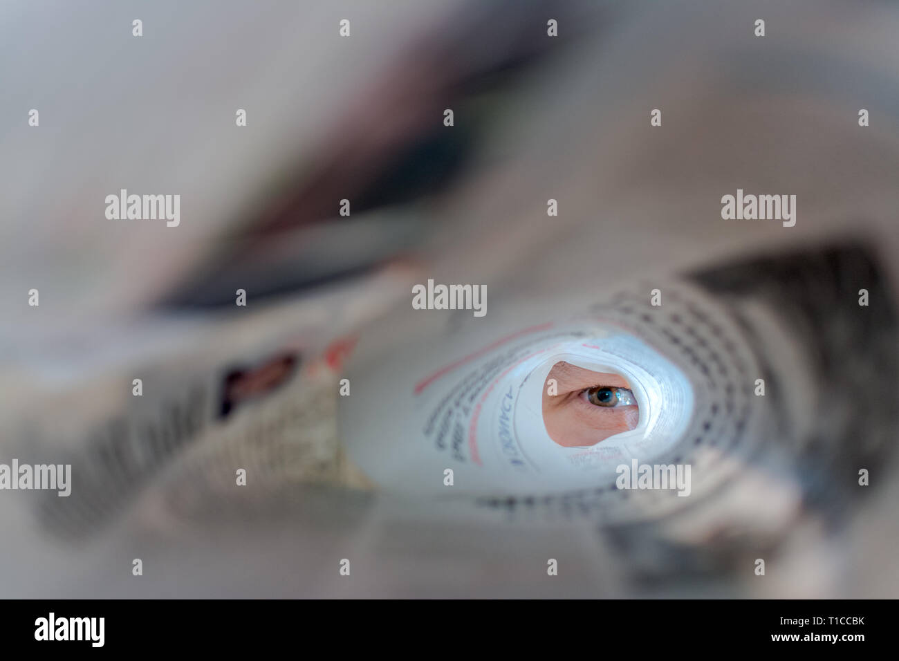 caucasian male eye looks through a rolled newspaper Stock Photo - Alamy