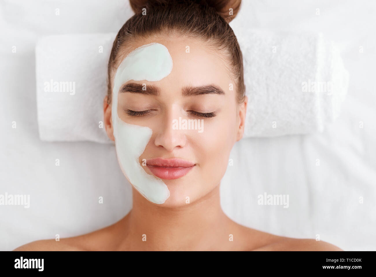 Beautiful young woman with facial mask on half of face Stock Photo - Alamy