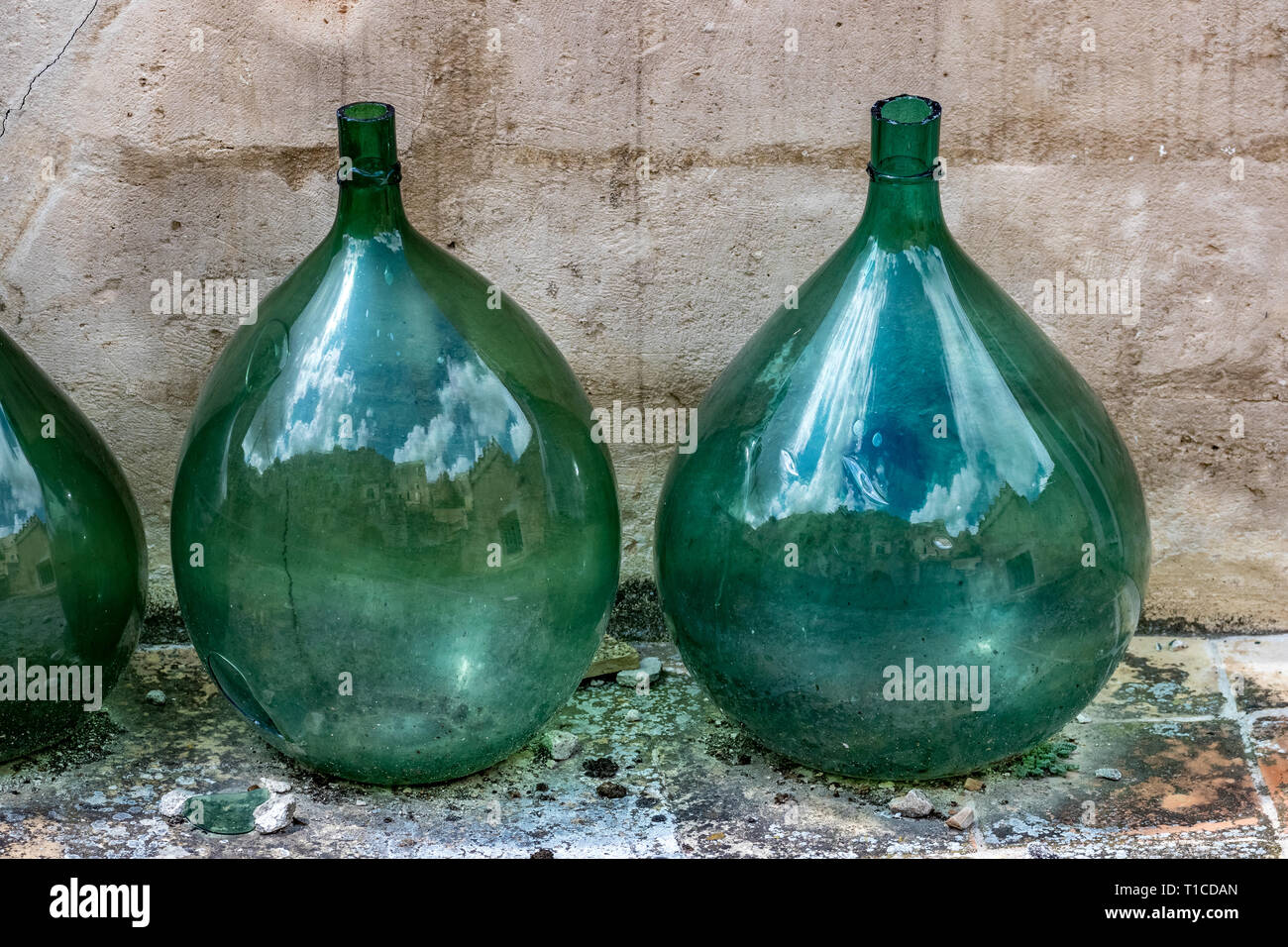 Two huge green glass empty wine jars placed in a row reflecting the ...