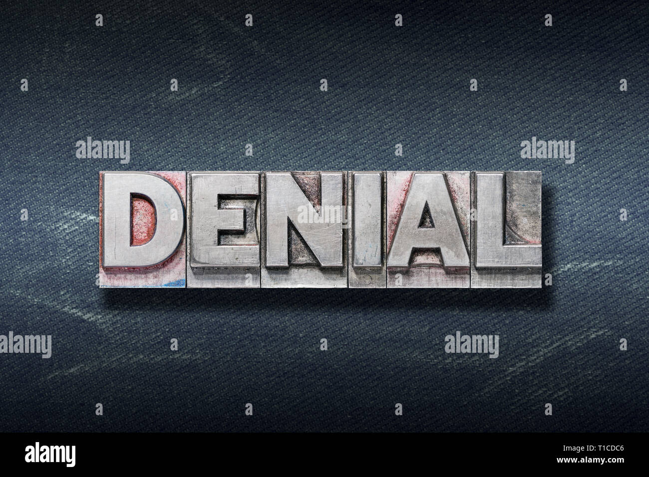 denial word made from metallic letterpress on dark jeans background ...