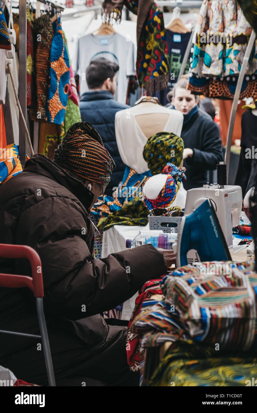 London, UK - March 16. 2019: Seller sewing at a fabric stall inside ...