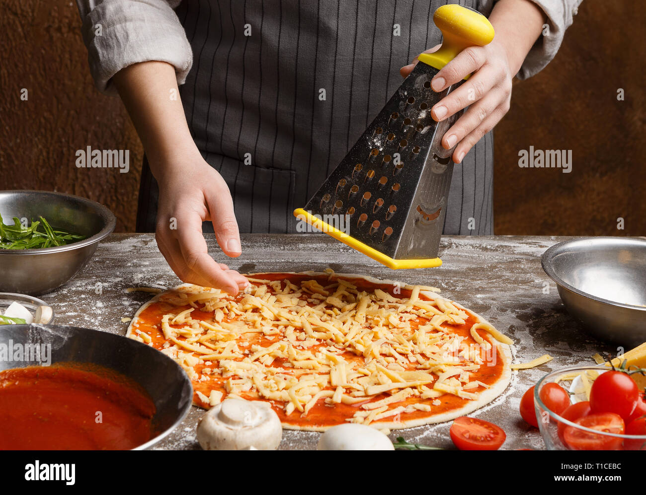 Preparing pizza. Woman rubbing cheese on grater Stock Photo - Alamy