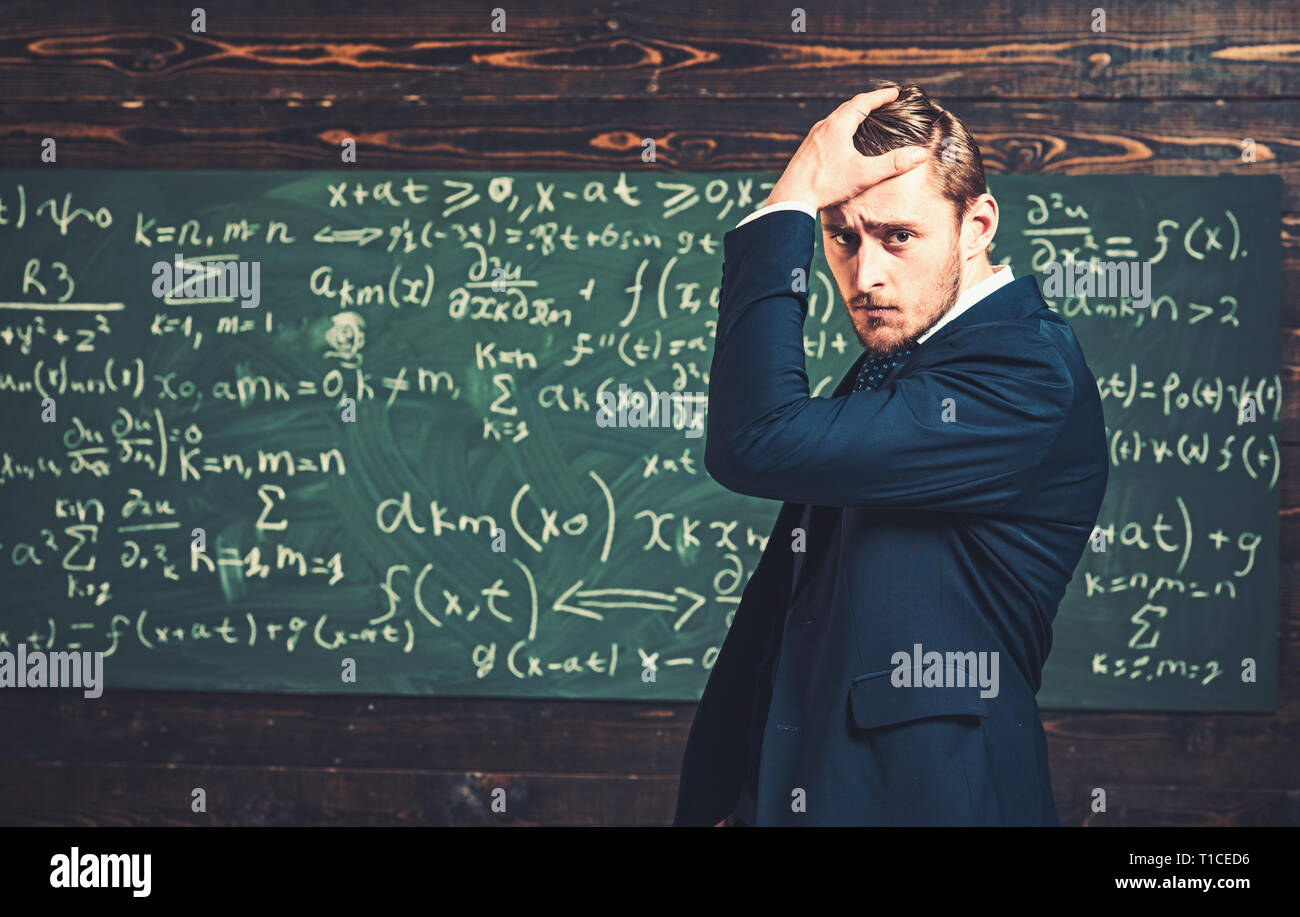 Thoughtful young man in elegant suit standing over green board full of ...