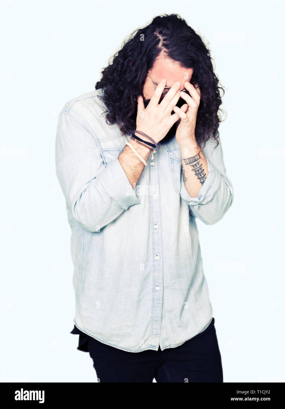 Young hipster man with long hair and beard wearing glasses with sad ...