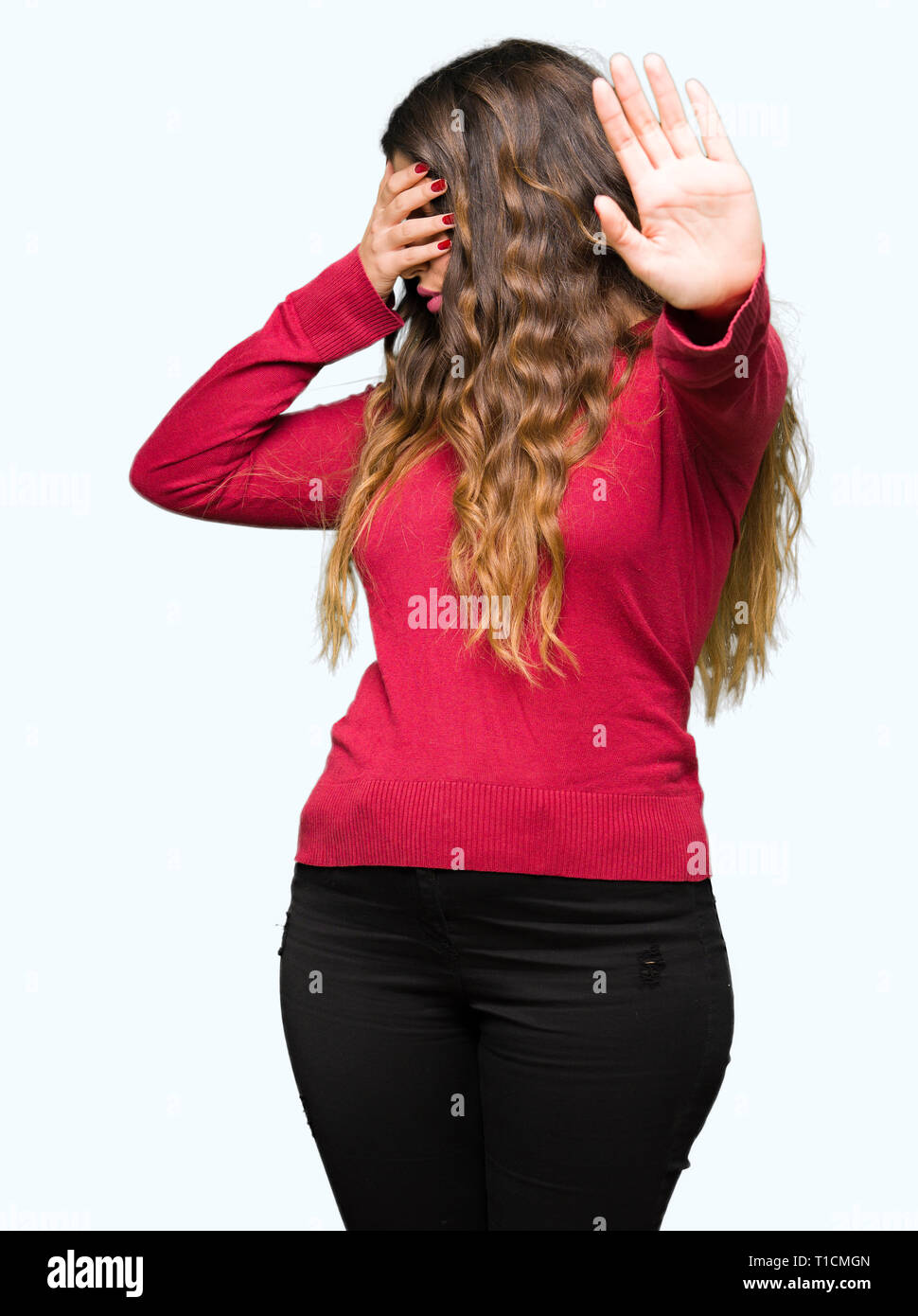 Young beautiful woman wearing red sweater covering eyes with hands and ...