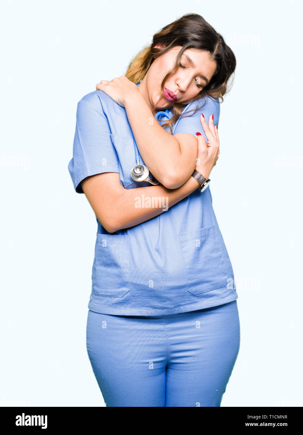 Young adult doctor woman wearing medical uniform Hugging oneself happy ...