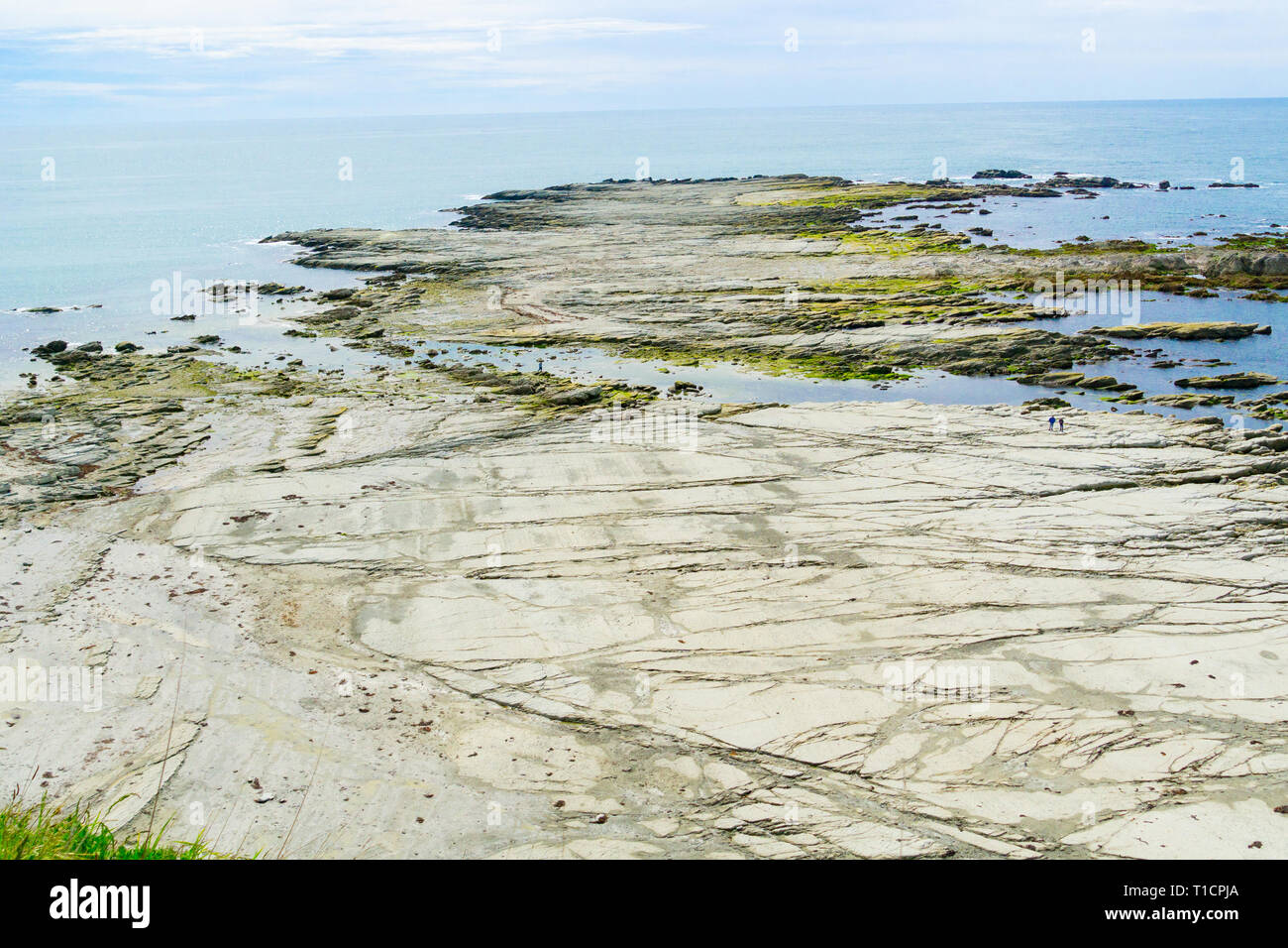 Large area Wide flat mud-rock ledge with small distant figures of ...
