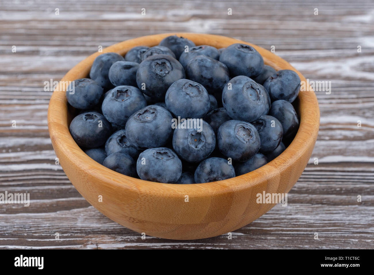 Ripe blueberries in wooden bowl on wood table background. Side view ...