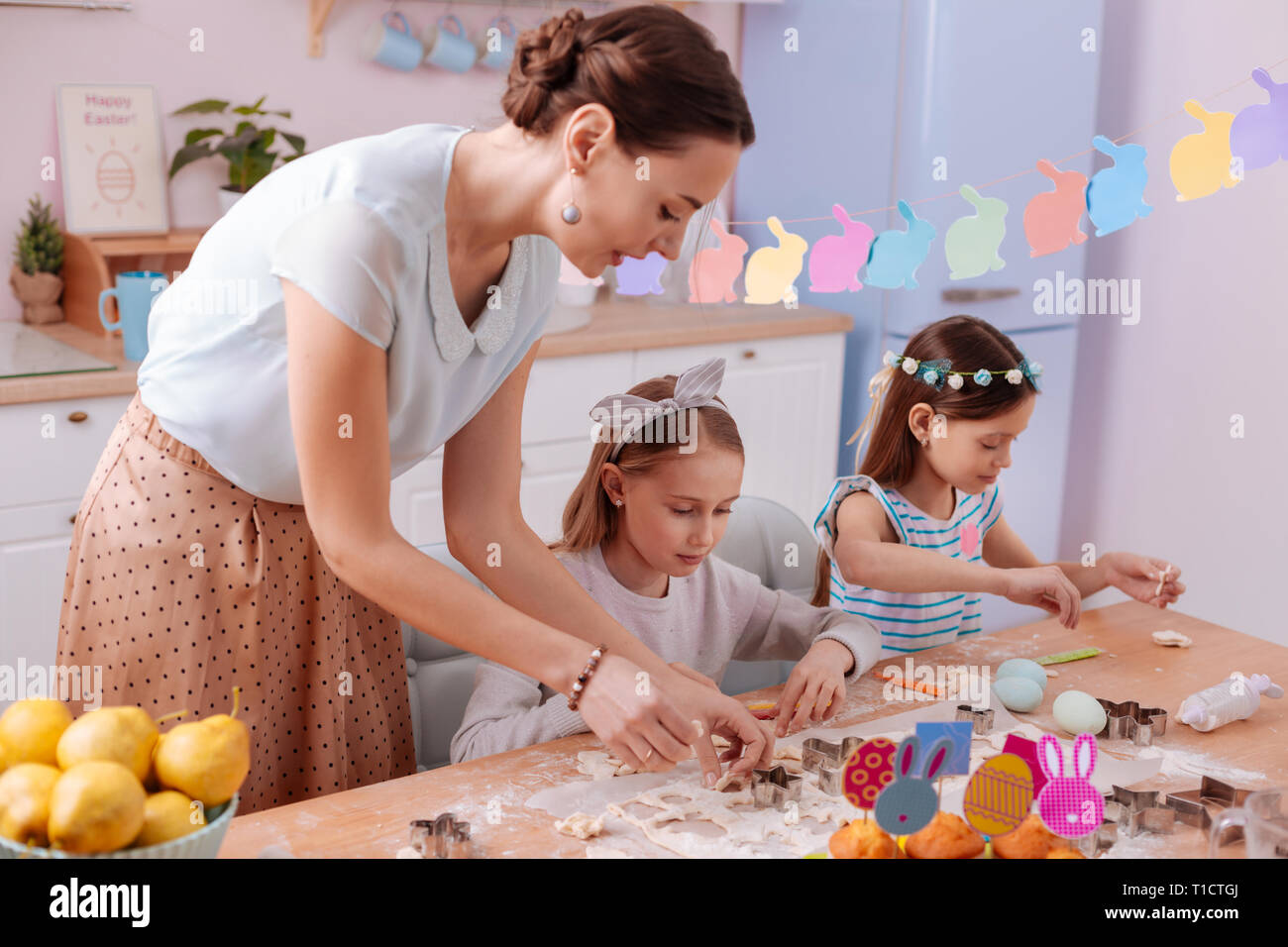 Cute girls doing cookies with their mom Stock Photo - Alamy