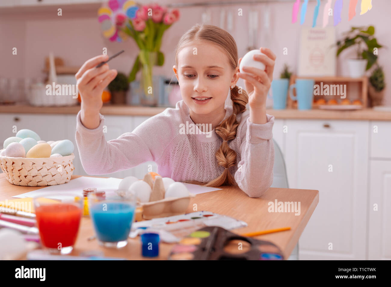 Cheerful blonde girl taking clean egg from holder Stock Photo - Alamy