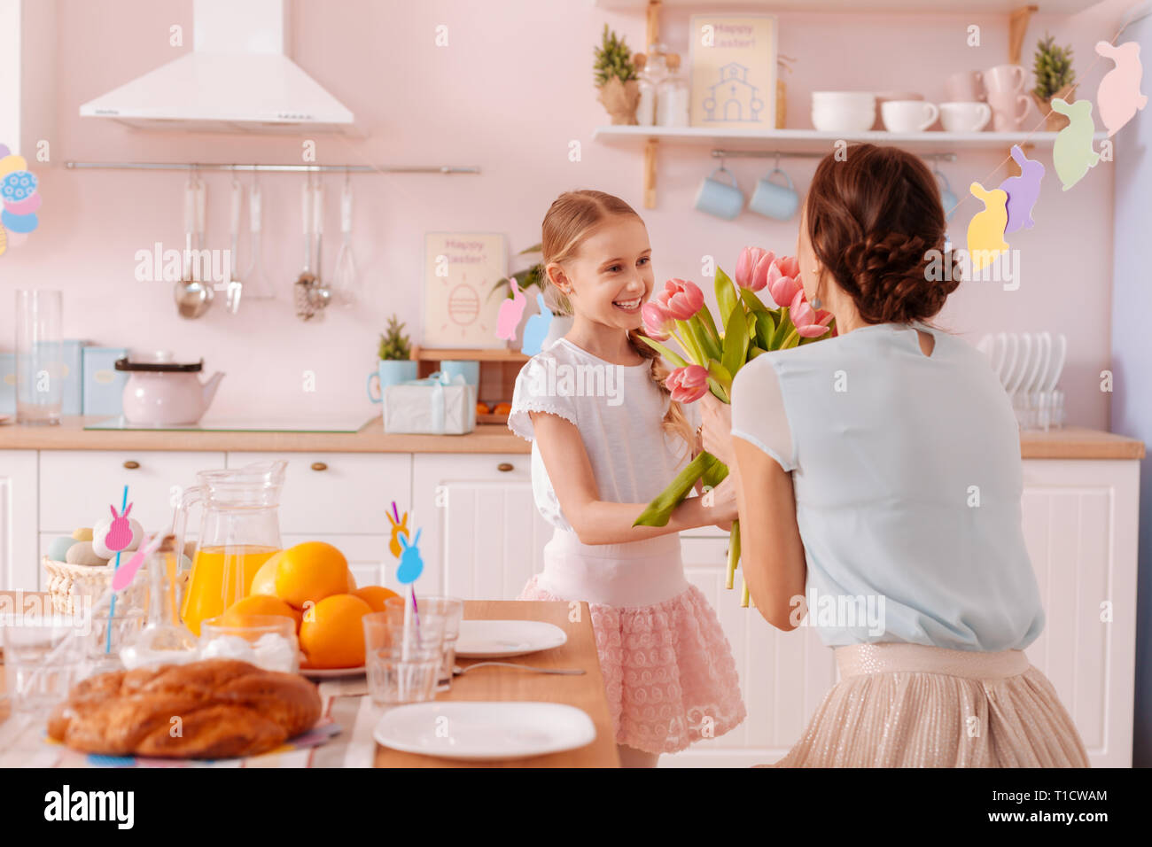 Positive delighted kid presenting flowers to her mom Stock Photo - Alamy