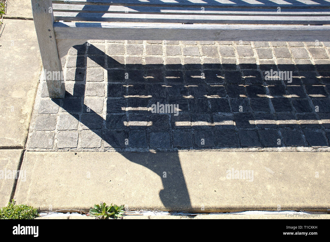 Weathered wooden park bench casting shadow Stock Photo - Alamy