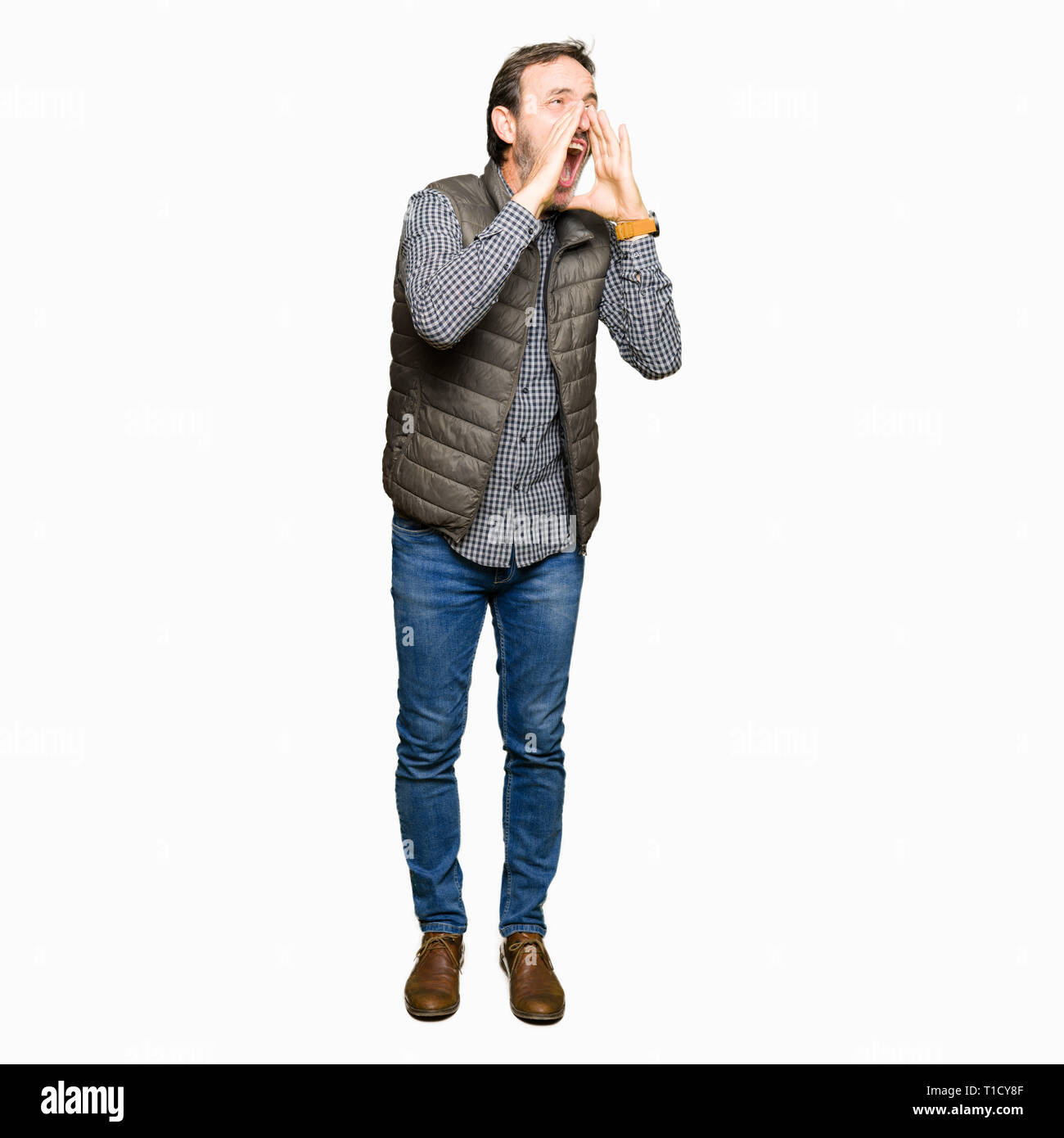 Middle age handsome man wearing winter vest Shouting angry out loud ...