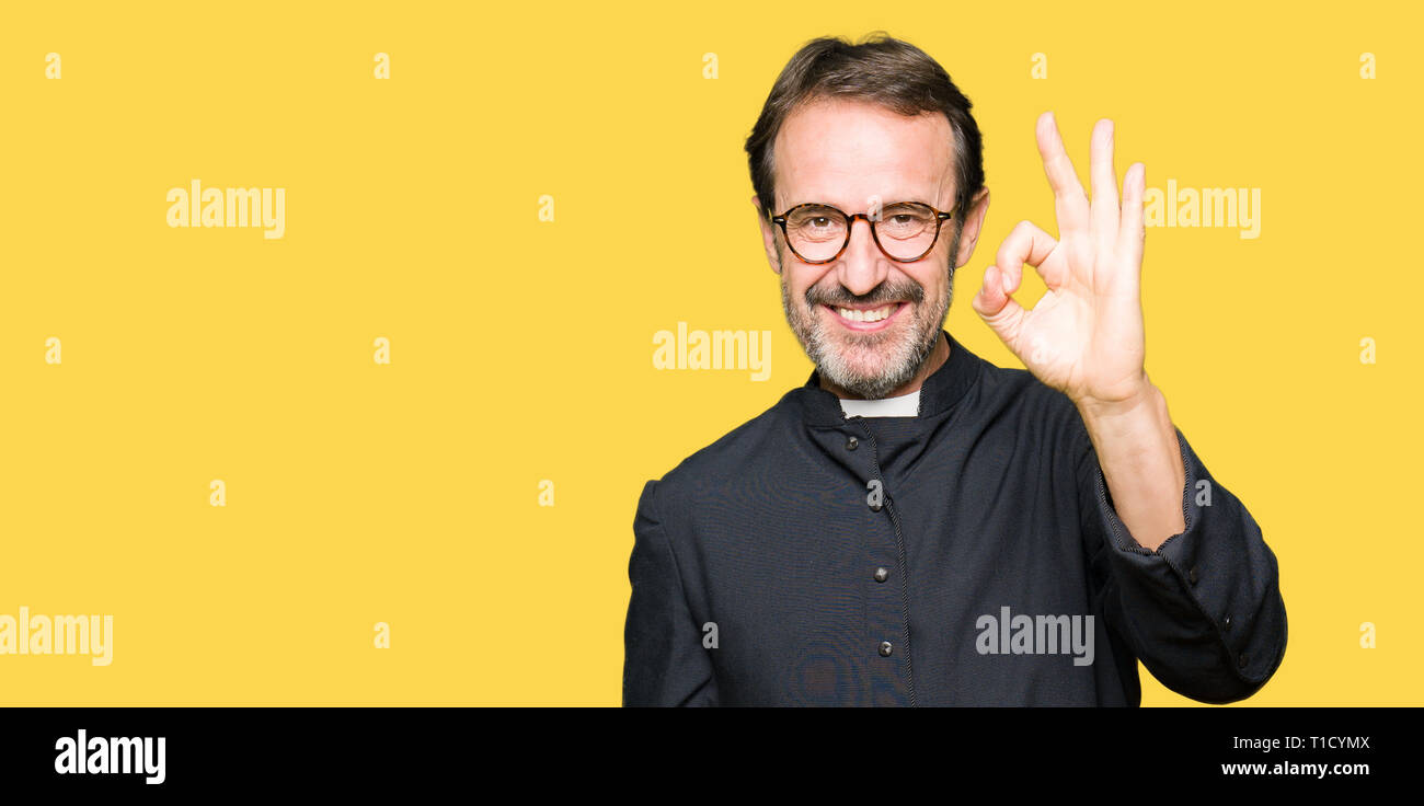Middle age priest man wearing catholic robe smiling positive doing ok ...