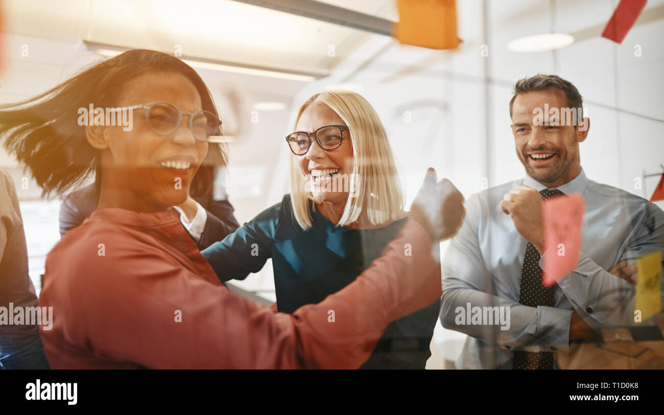 Two ecstatic young businesswomen laughing while brainstorming with ...