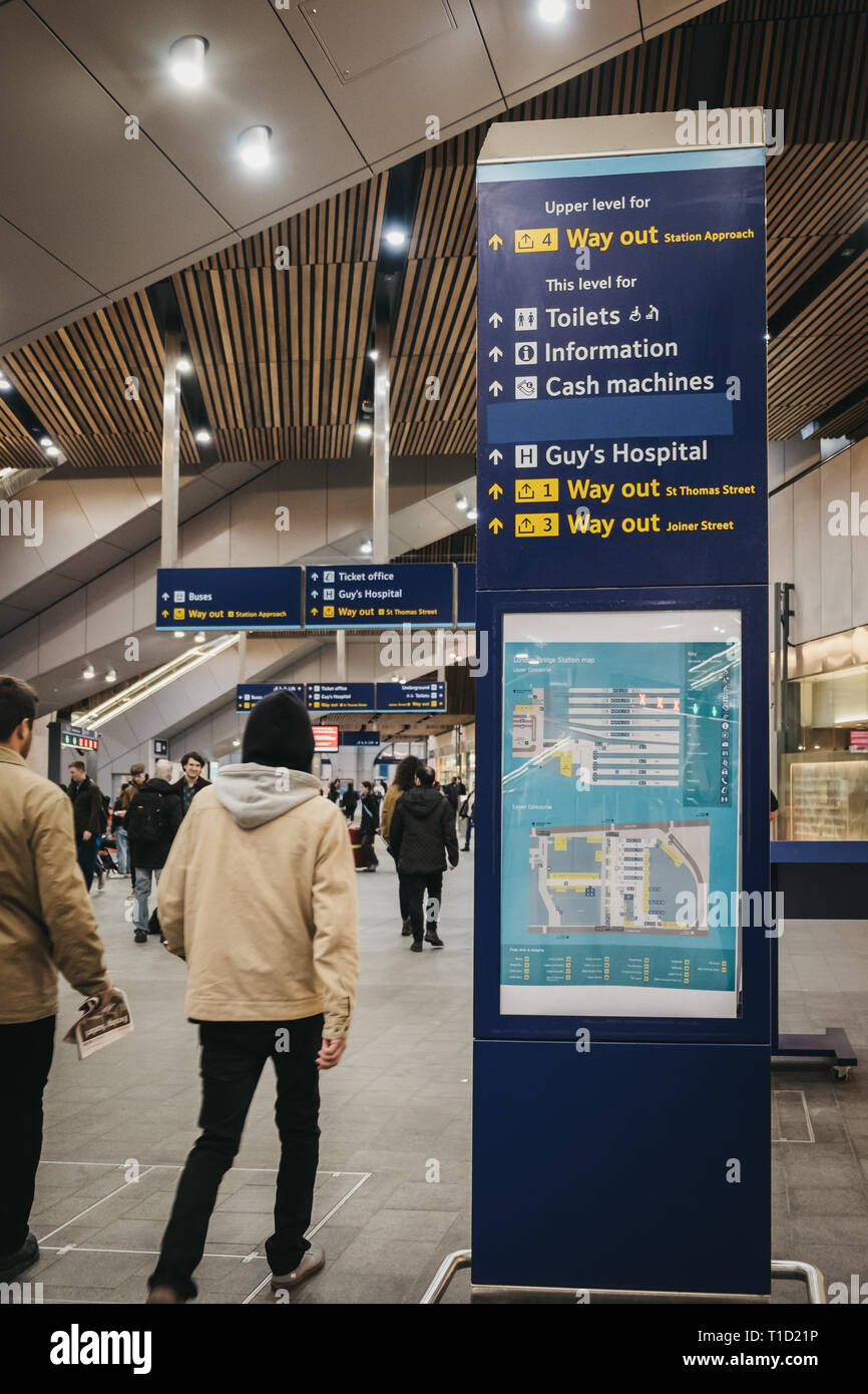 London, UK - March 16, 2019: People walking past directional sign ... London, UK - March 16, 2019: People walking past directional sign ...