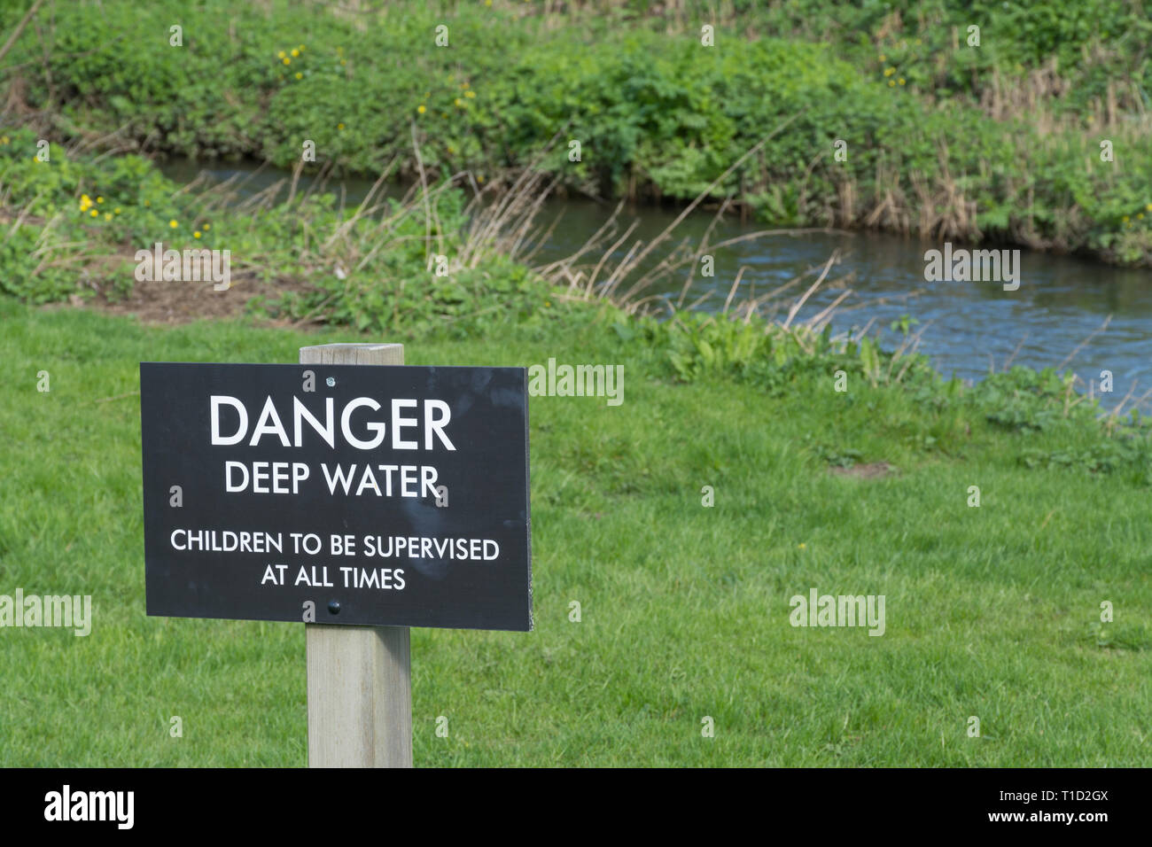 Sign next to a river warning Danger deep water, children to be ...