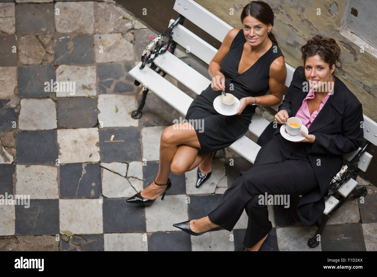 Portrait of two smiling mid-adult business woman sitting drinking ...