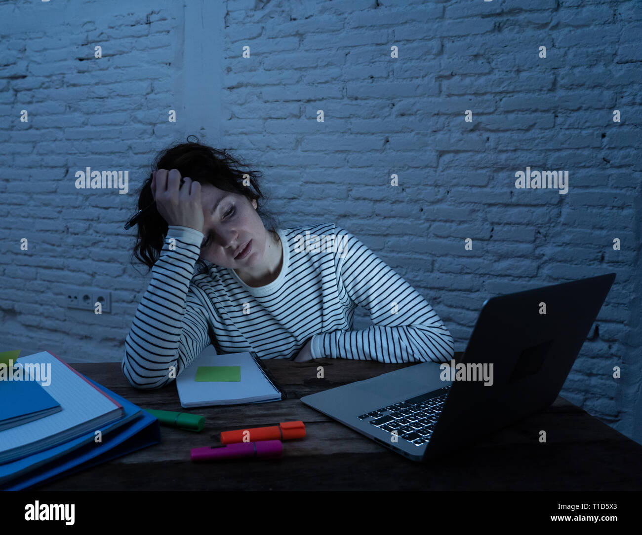 Overworked and tired female student working late at night on laptop ...