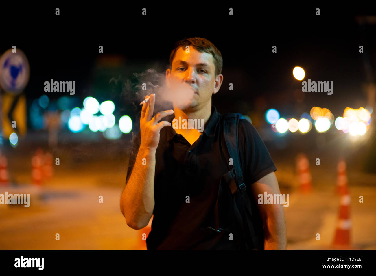 man smoking a cigarette on the street at night Stock Photo - Alamy