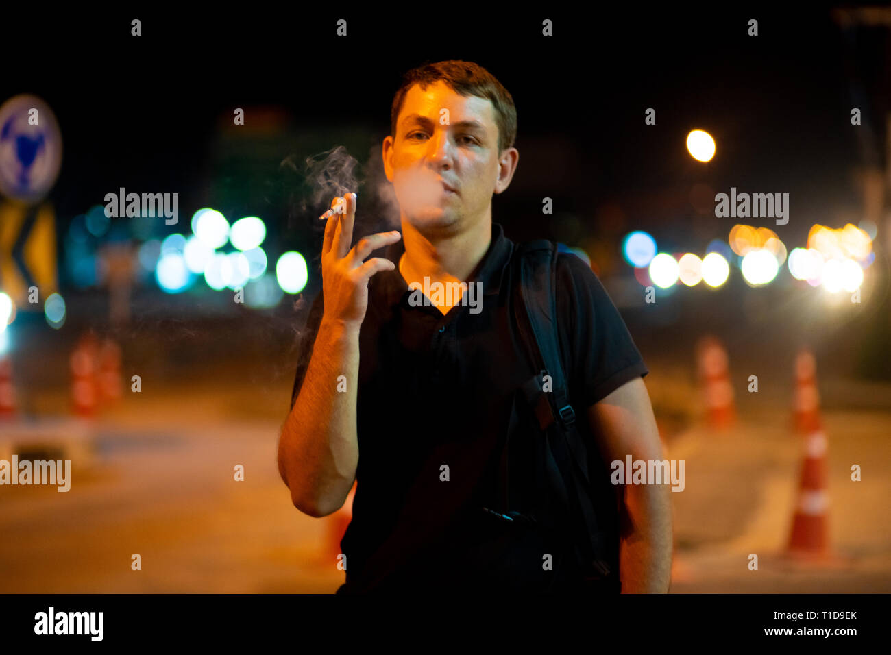 man smoking a cigarette on the street at night Stock Photo - Alamy