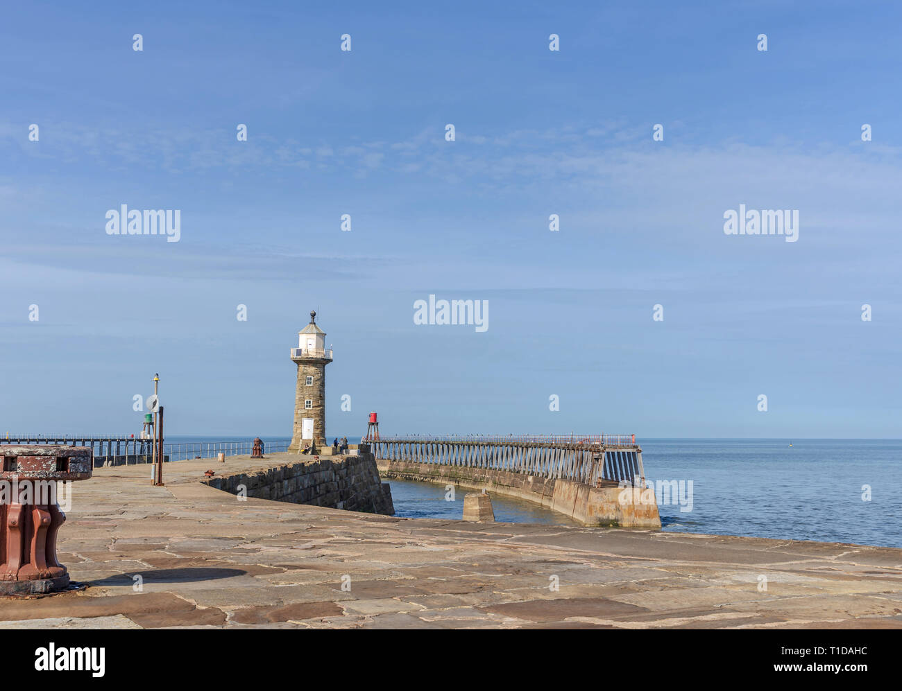 Whitby harbour entrance. A lighthouse is at the end of a curving pier ...