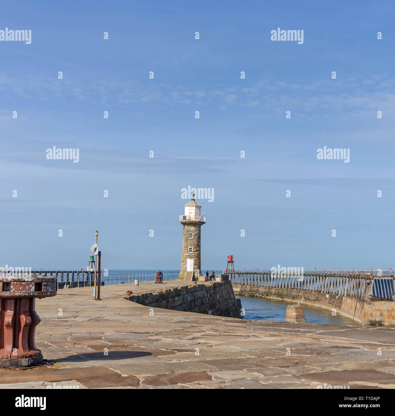Whitby harbour entrance. A lighthouse is at the end of a curving pier ...