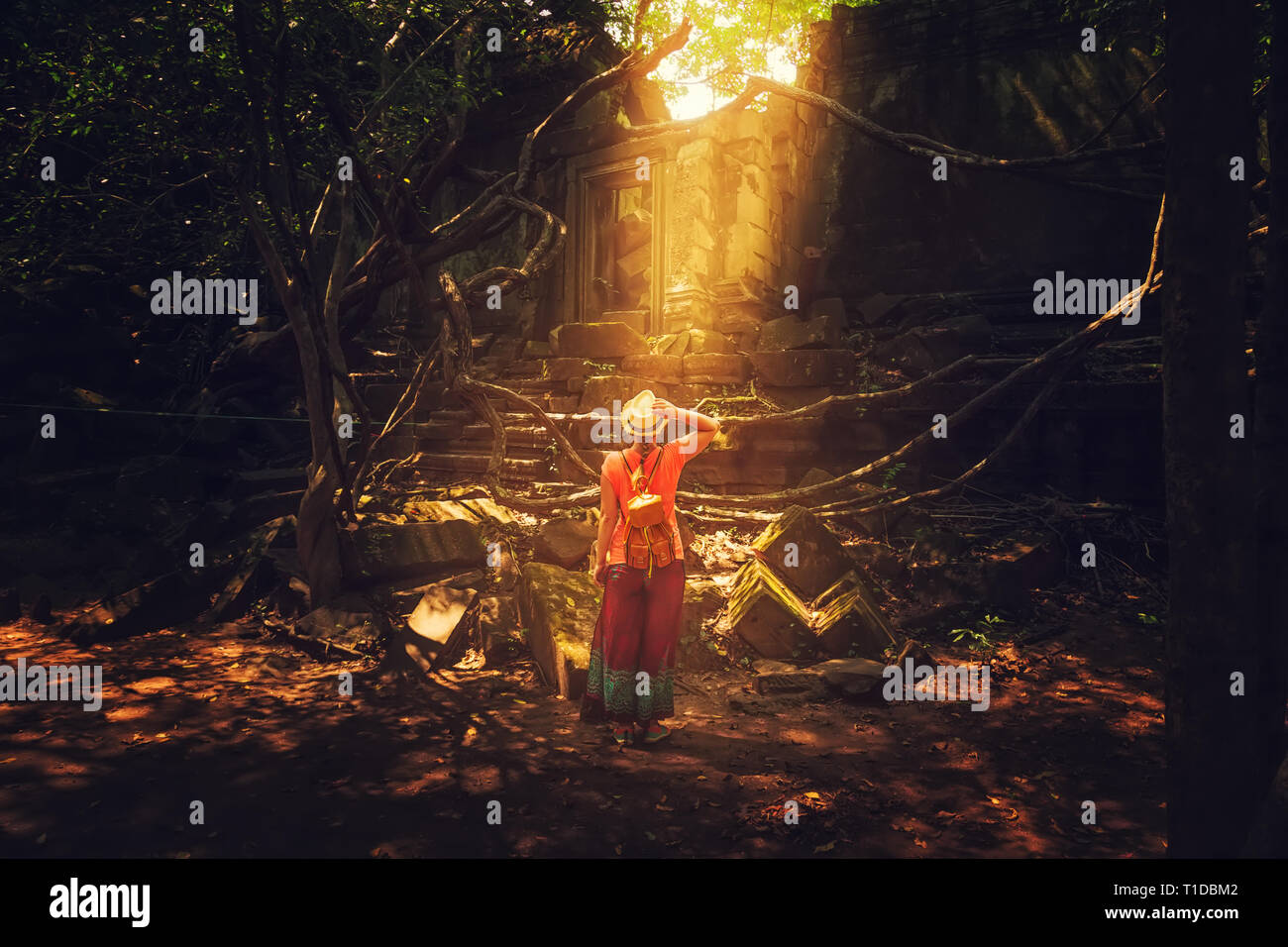 The girl in the jungle looks at the ruins of the temple of Beng Mealea ...