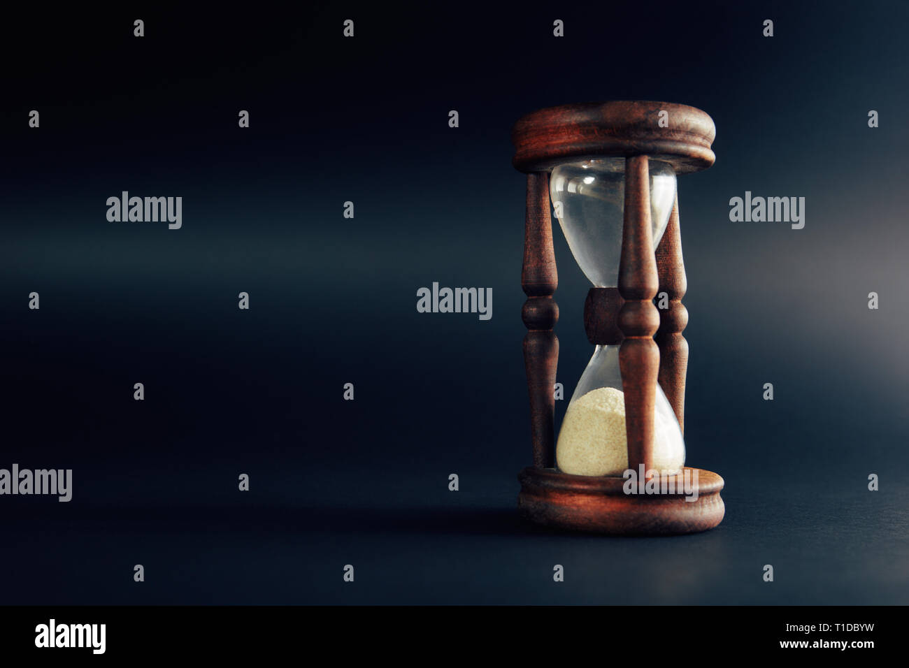 sand clock on a black background with long shadows Stock Photo - Alamy
