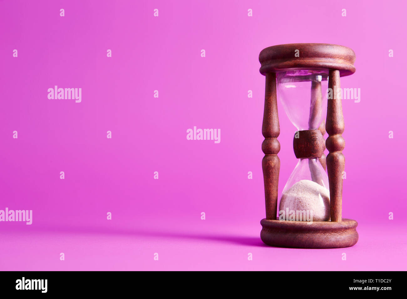 sand clock on a purple background with long shadows Stock Photo - Alamy