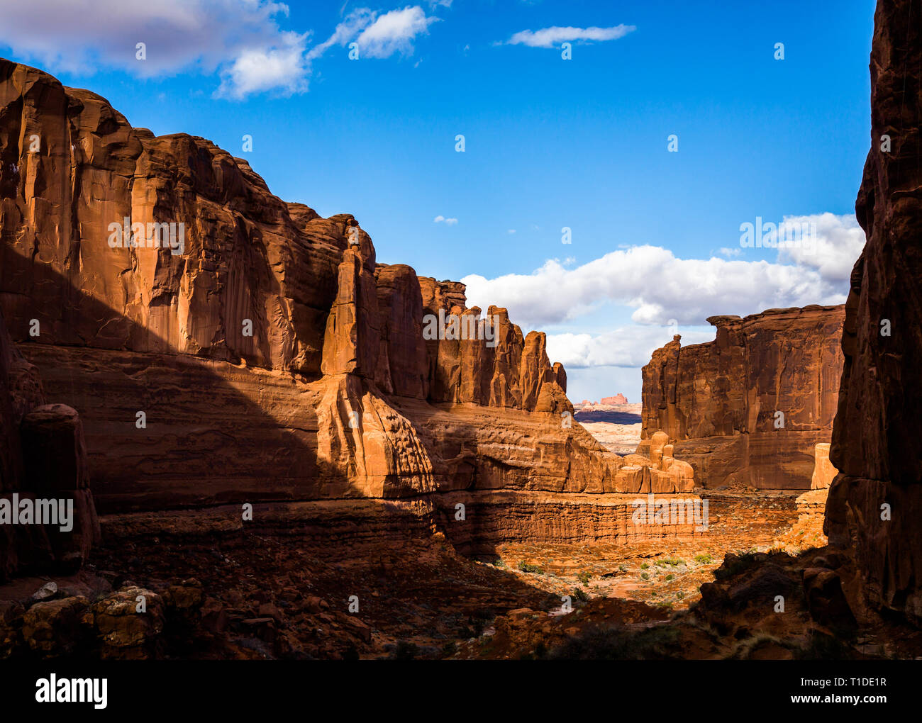 Light shining through clouds into a wide canyon of Arches National Park ...