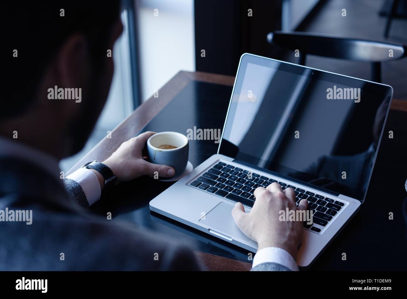 Good looking young man in full suit using computer while sitting in the ...