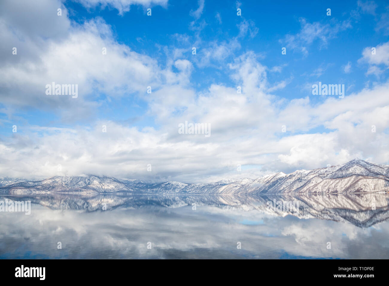 Calm shallow water perfectly reflects the sky and mountains around Lake ...