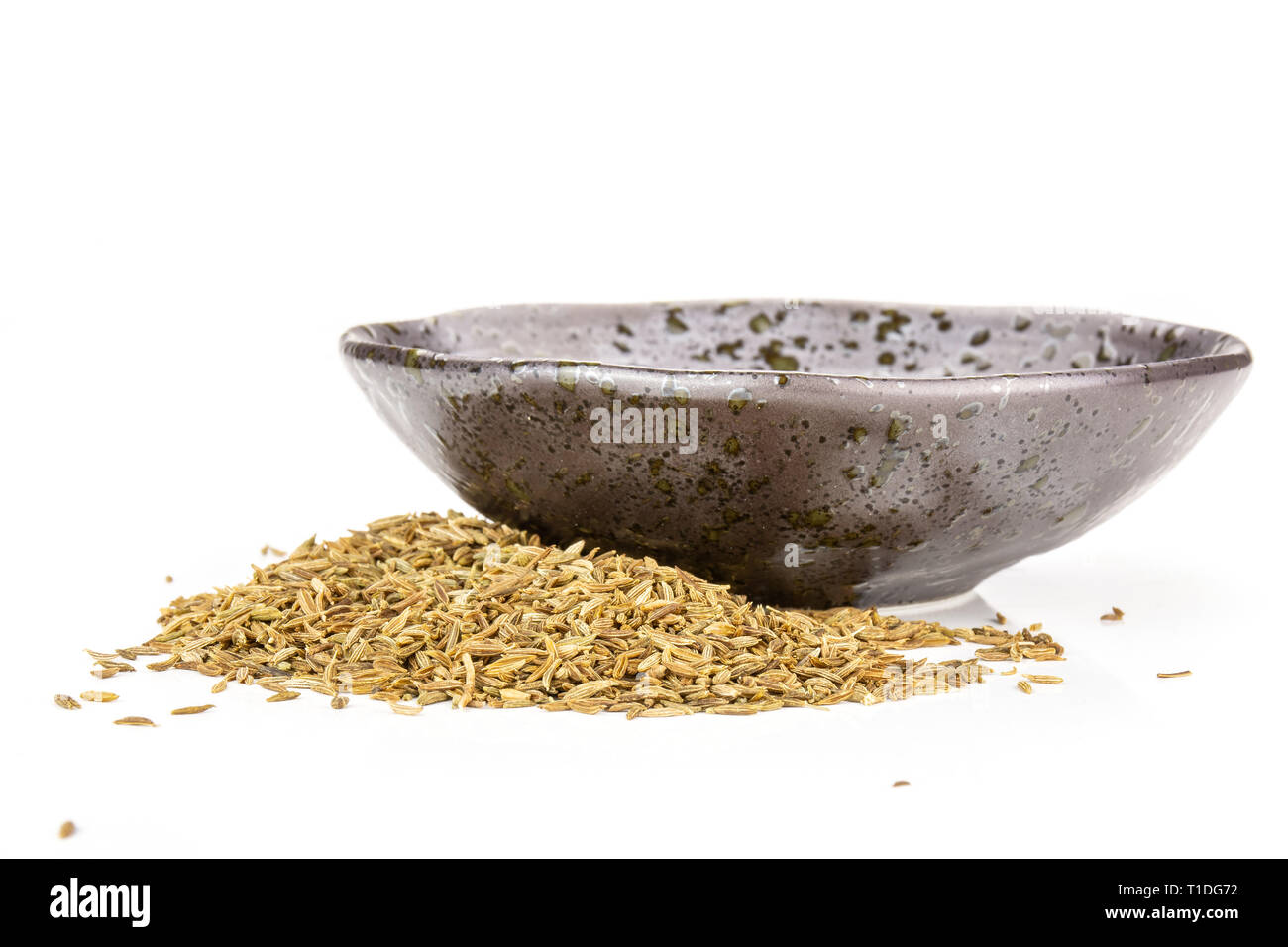 Lot of whole roman caraway seeds in a grey ceramic bowl isolated on ...