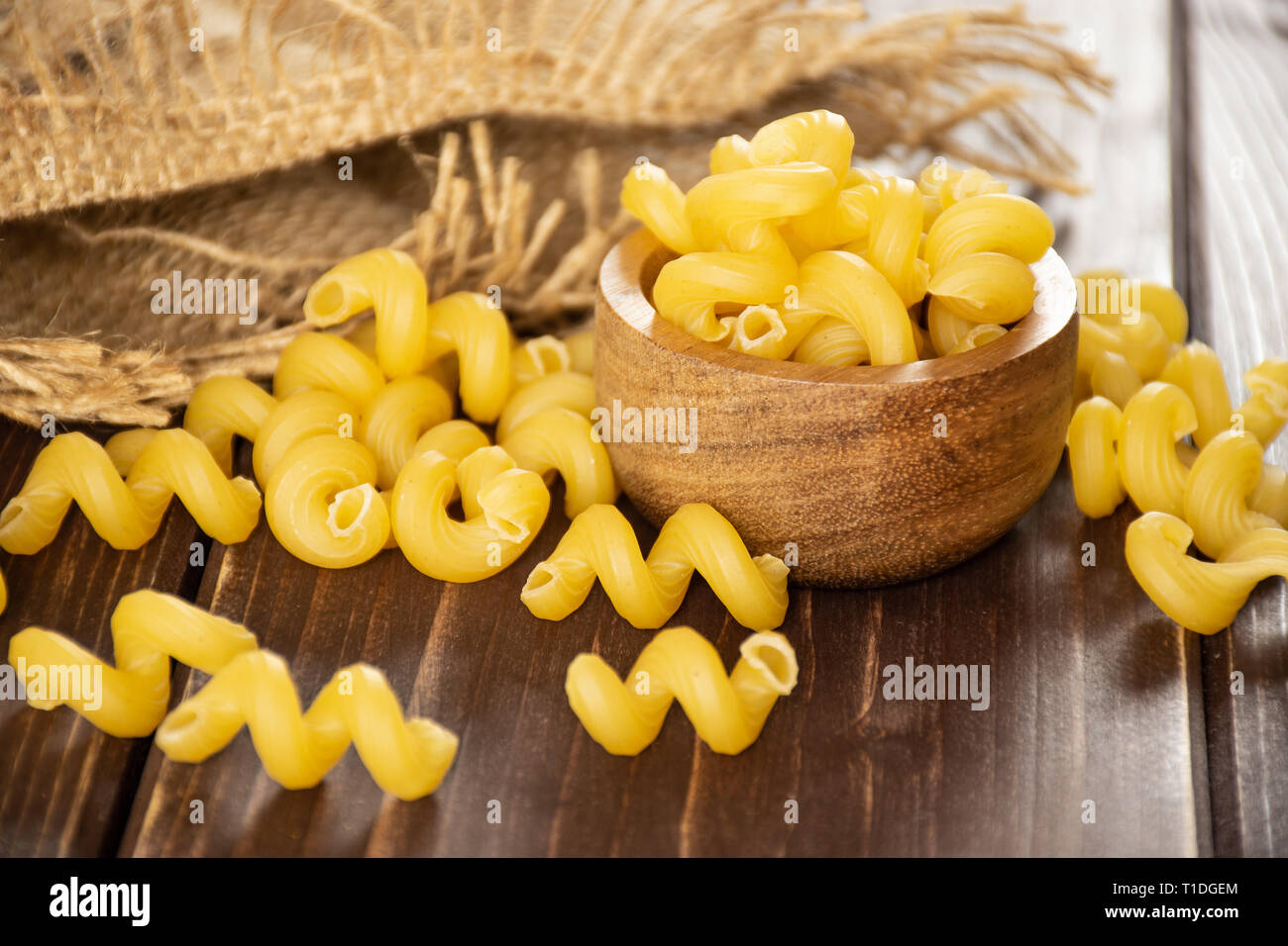 Lot of whole pasta cavatappi with wooden bowl in a jute bag on brown ...