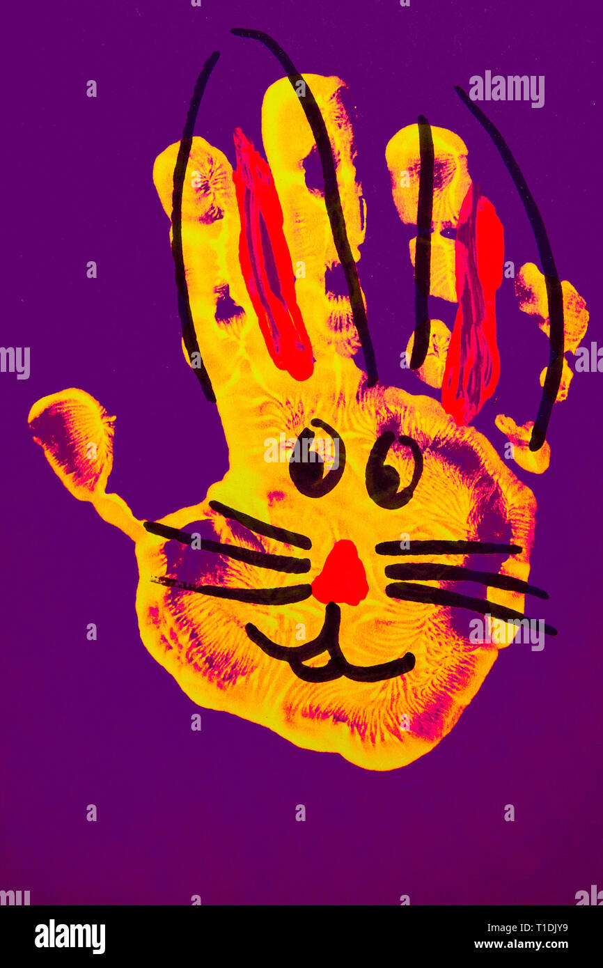 Easter bunny from yellow red kids hand imprint on purple background ...