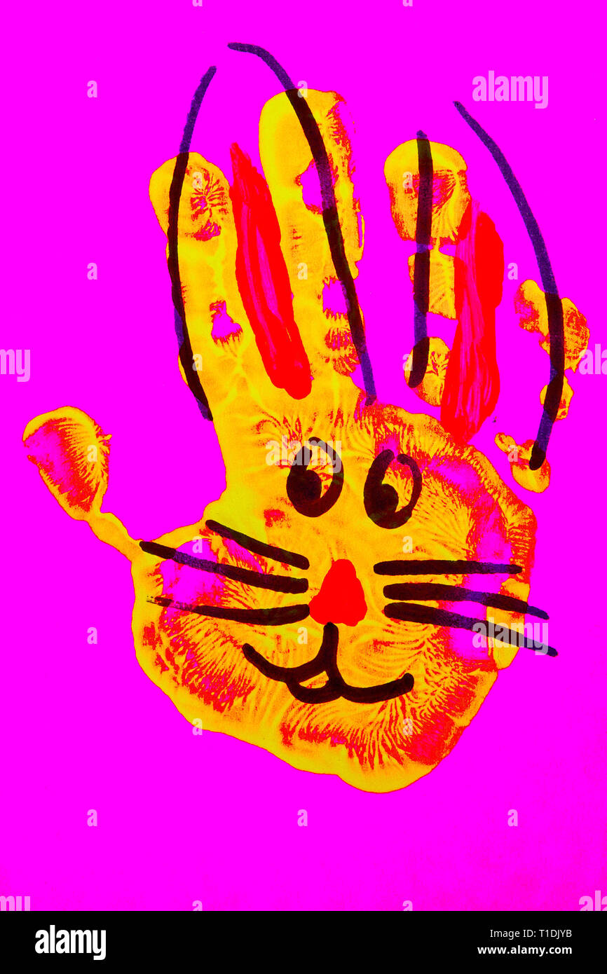 Easter bunny from yellow red kids hand imprint on pink background ...