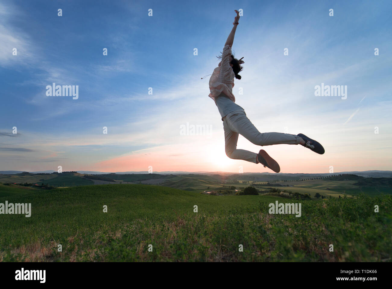 Freedom concept. A woman jumping in front of a beautiful Tuscany ...
