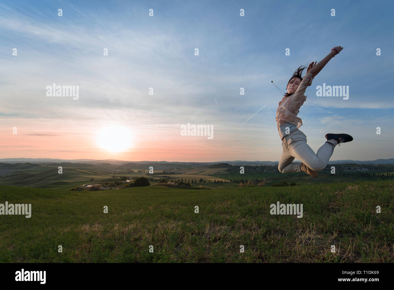 Freedom concept. A woman jumping in front of a beautiful Tuscany ...