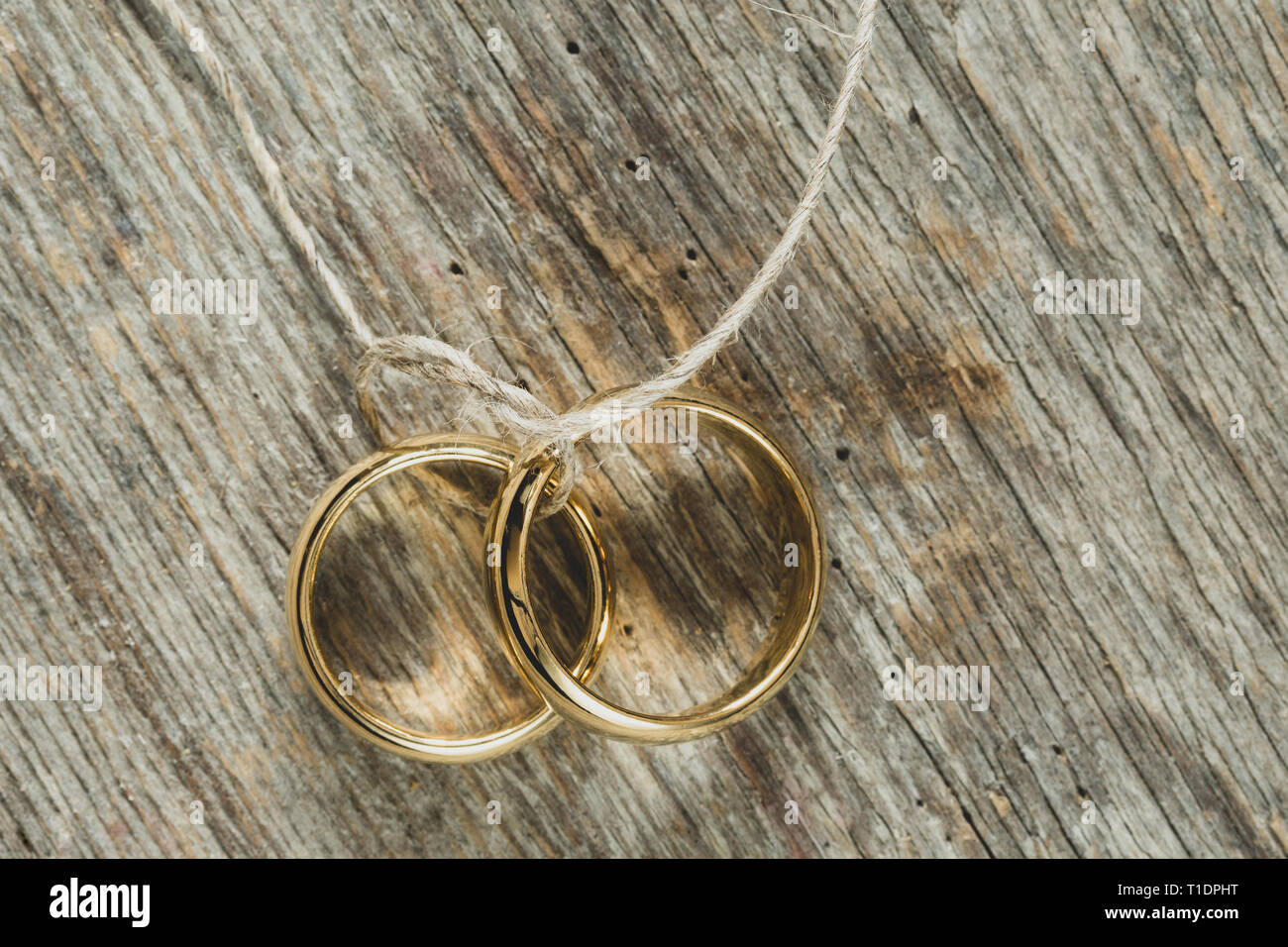 Two gold wedding rings tied with string over wood background Stock ...