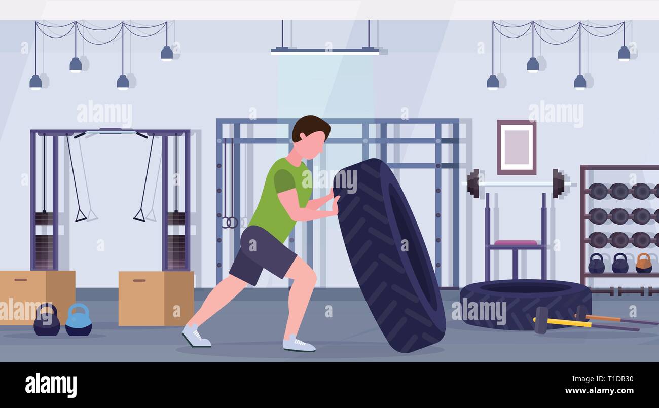 sports man flipping a tire doing hard exercises guy working out in gym ...
