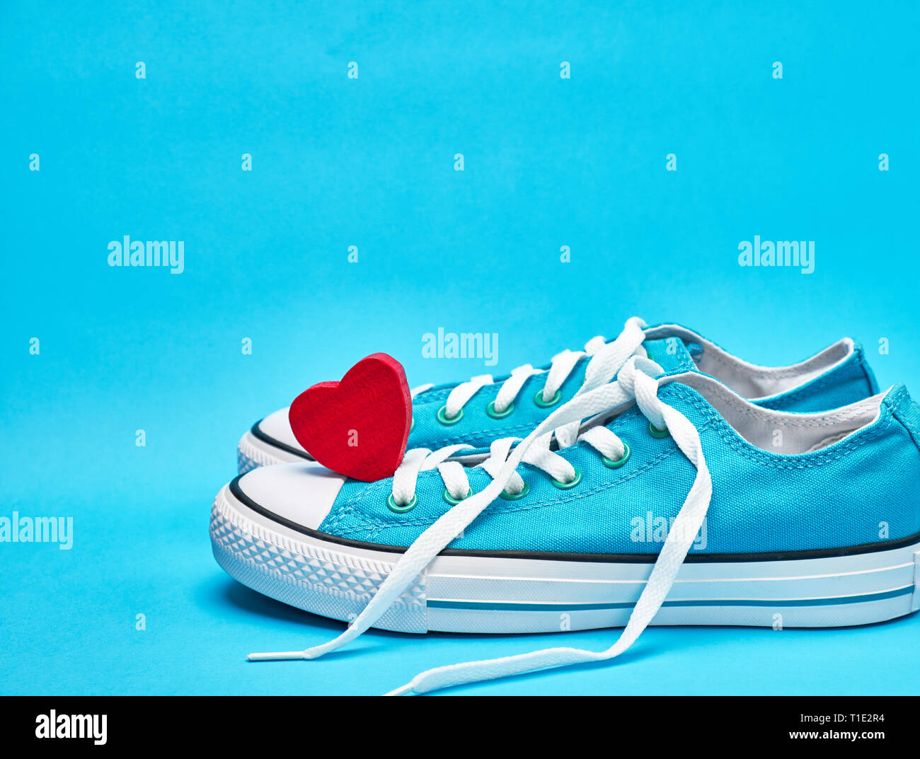 pair of blue textile sneakers with white untied laces and red heart ...