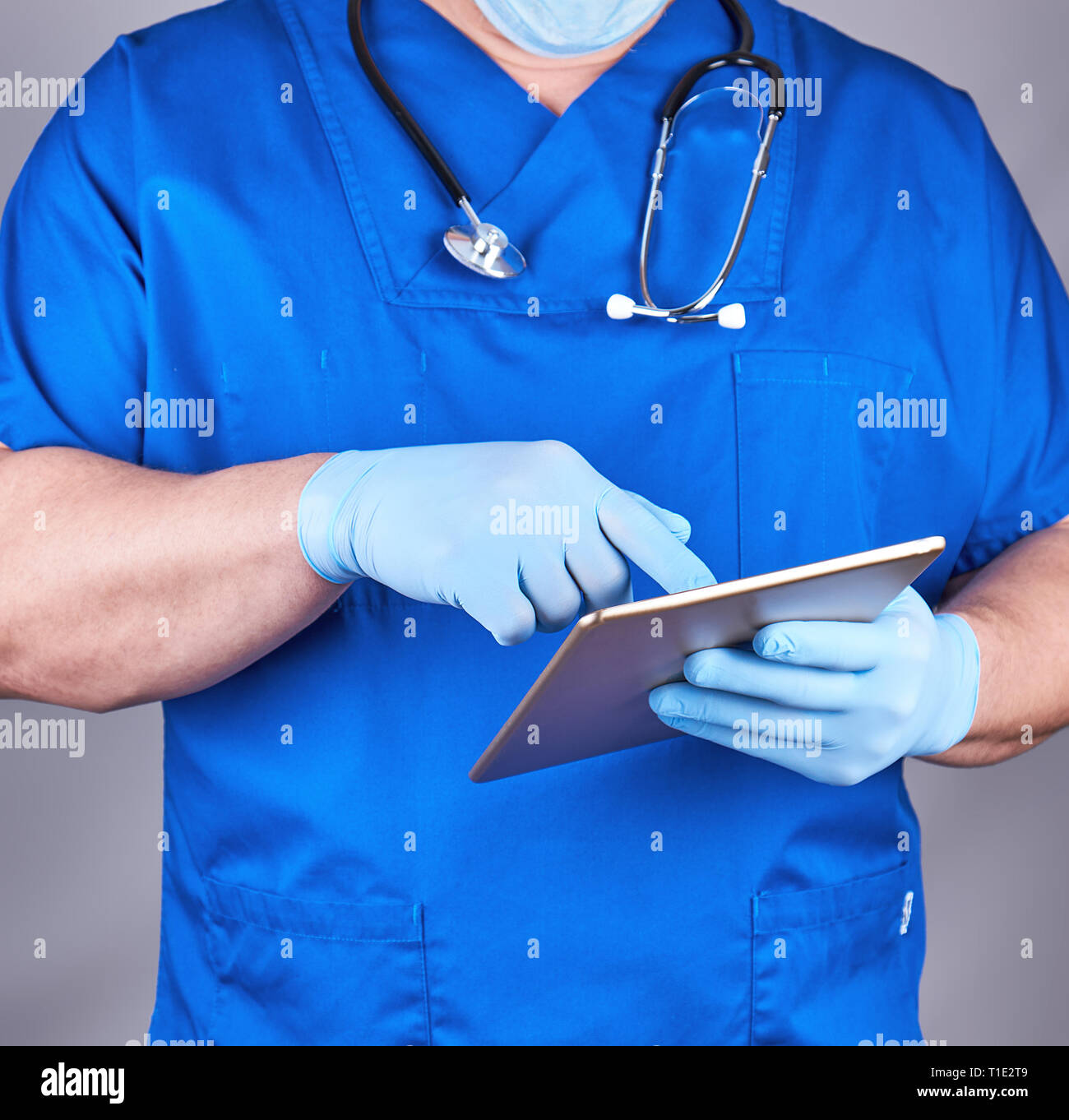 doctor in blue uniform and latex sterile gloves holding an electronic ...