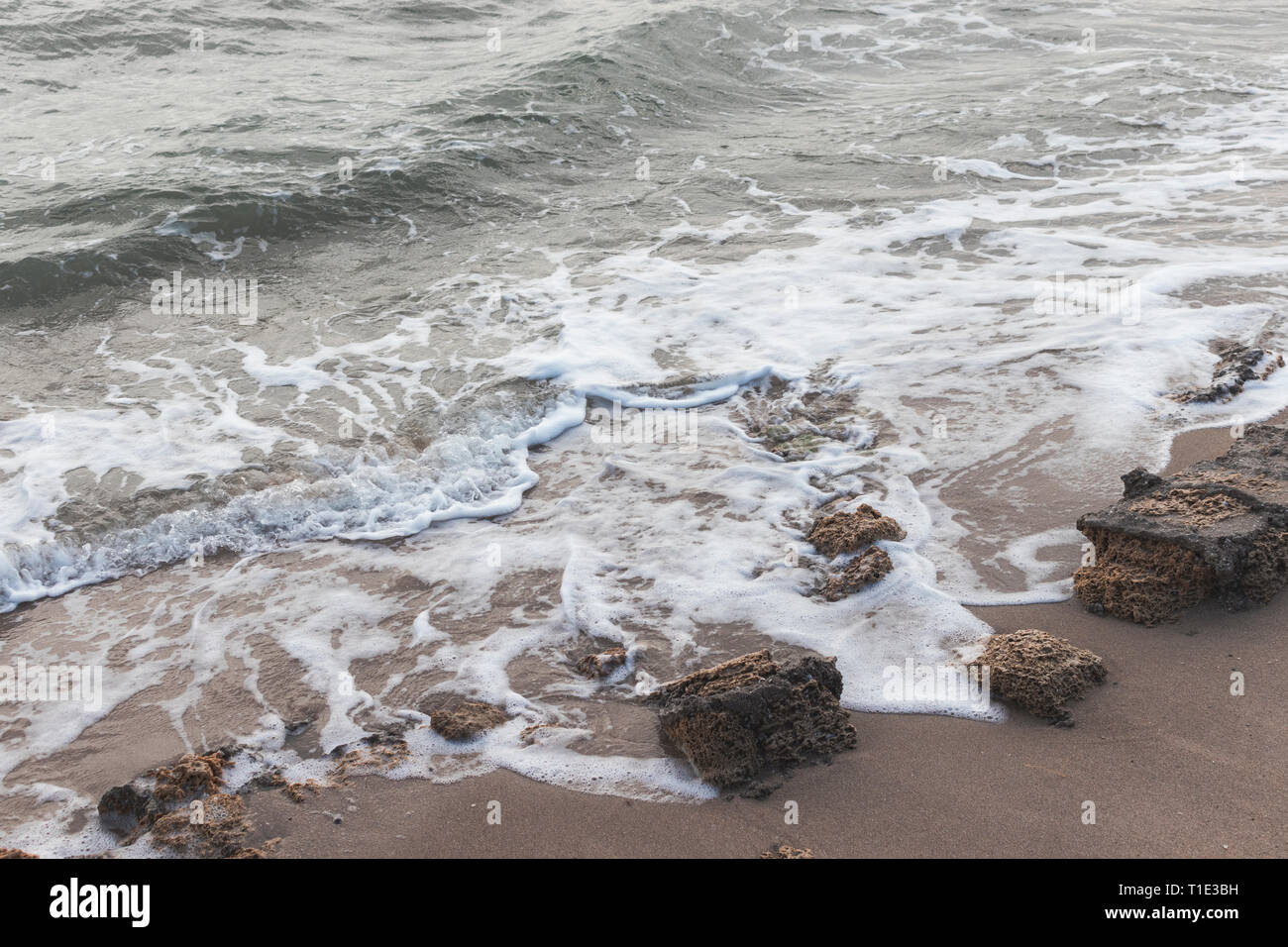 Sea shore. Stones on the sand. Ocean waves with white foam hitting ...