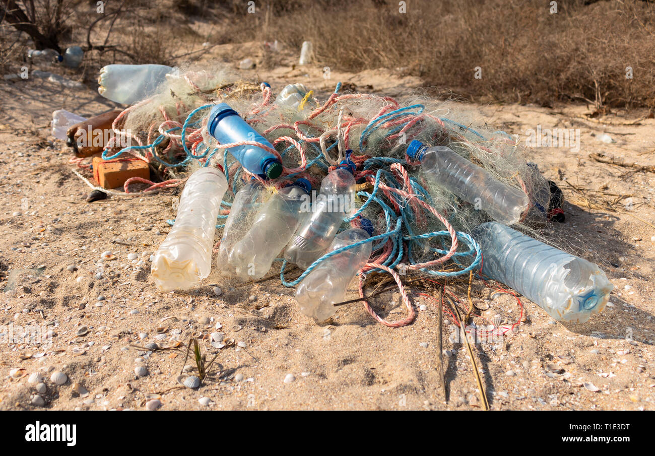 Empty plastic bottles and fishing nets on the sand. Garbage on the ...
