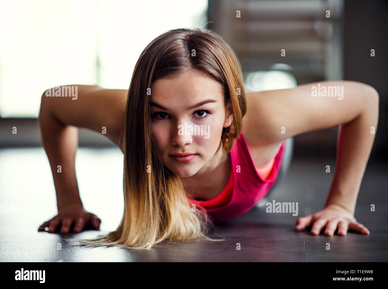 A portrait of young girl or woman doing push-ups in a gym Stock Photo ...