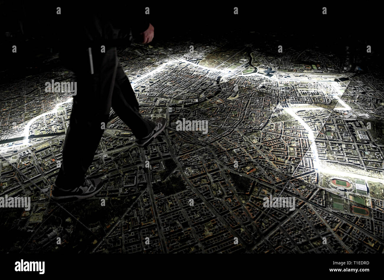 Berlin, Germany. 25th Mar, 2019. A young man walks over an illuminated ...